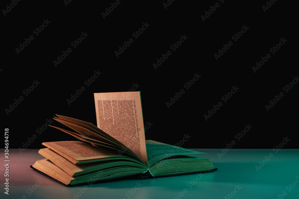 Beautiful open book in the color light on a table and night background ...