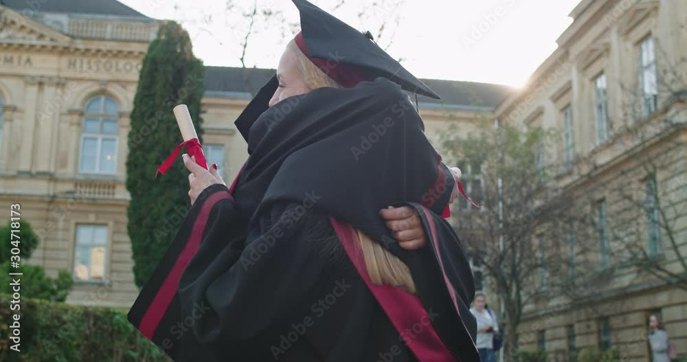 Two mixed-races young pretty girls friends, graduated students hugging ...