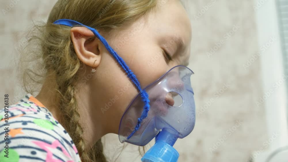 child with a tablet is sick and breathes through an inhaler. close-up ...
