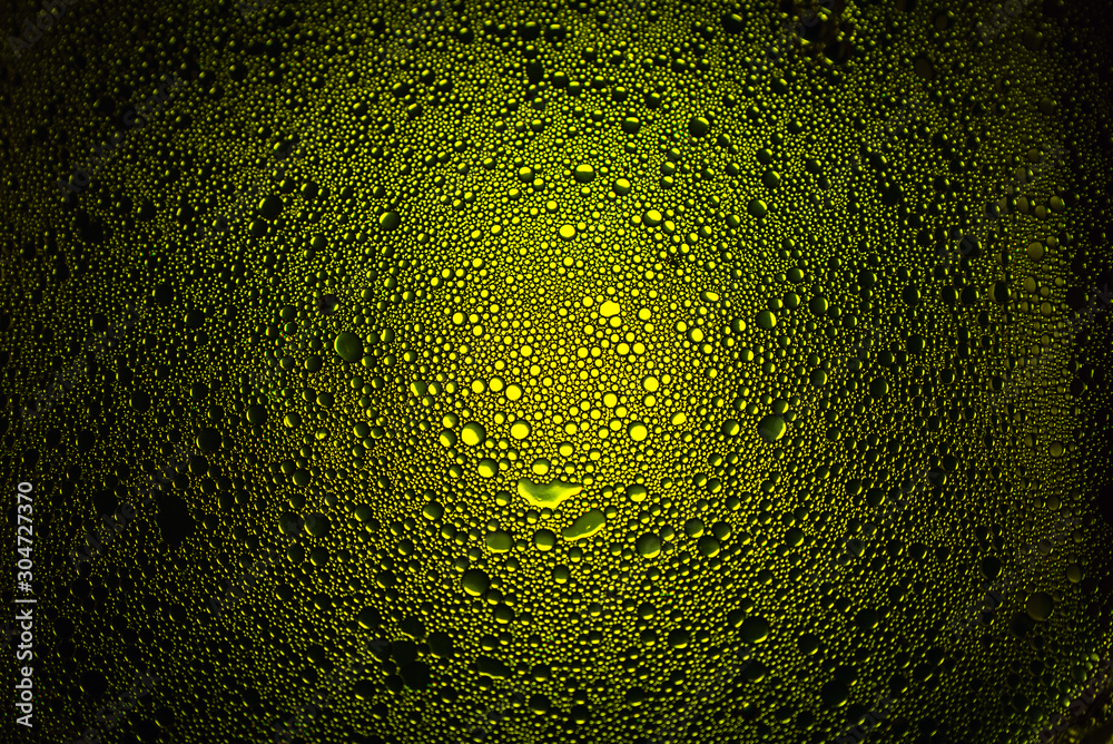 yellow oil droplets from a mixture of water and olive oil illuminated ...