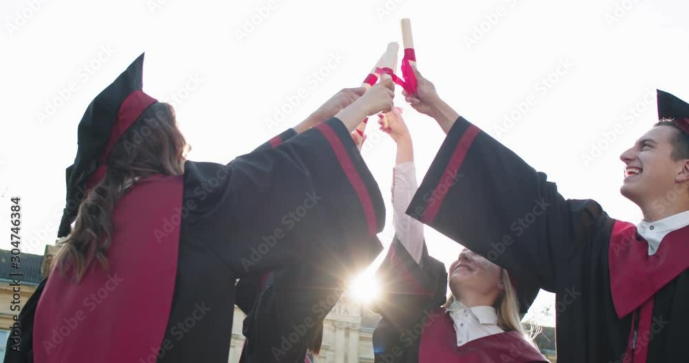 View from below on the happy young male and female graduates in ...