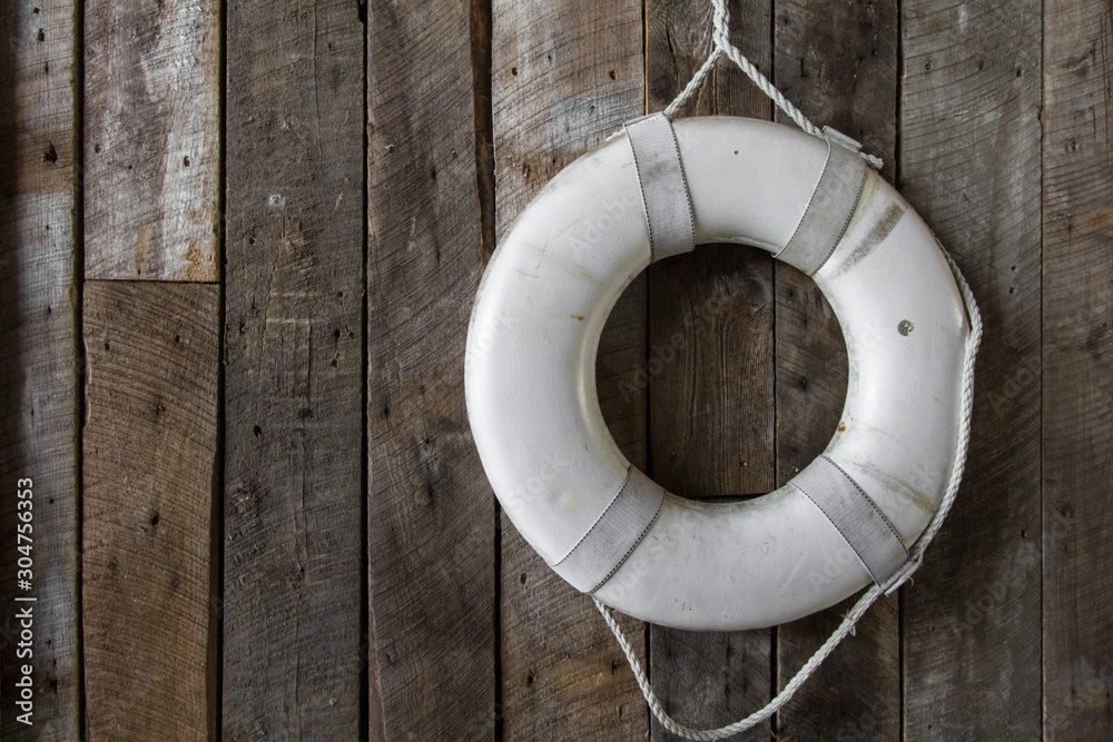 Life ring on a rustic wood wall with copy space. Stock Photo | Adobe Stock