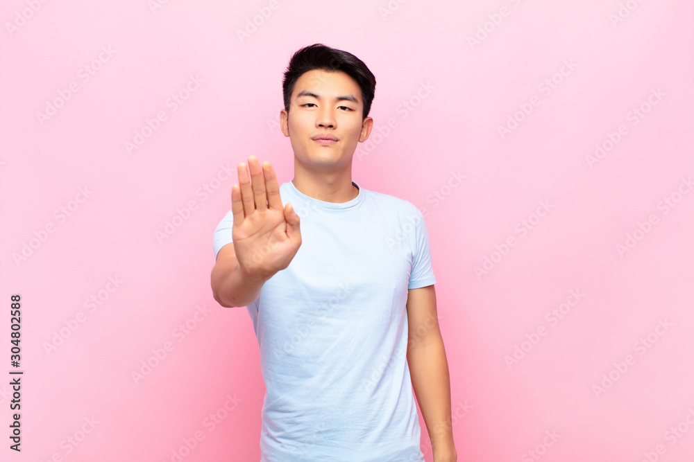 young chinese man looking serious, stern, displeased and angry showing ...