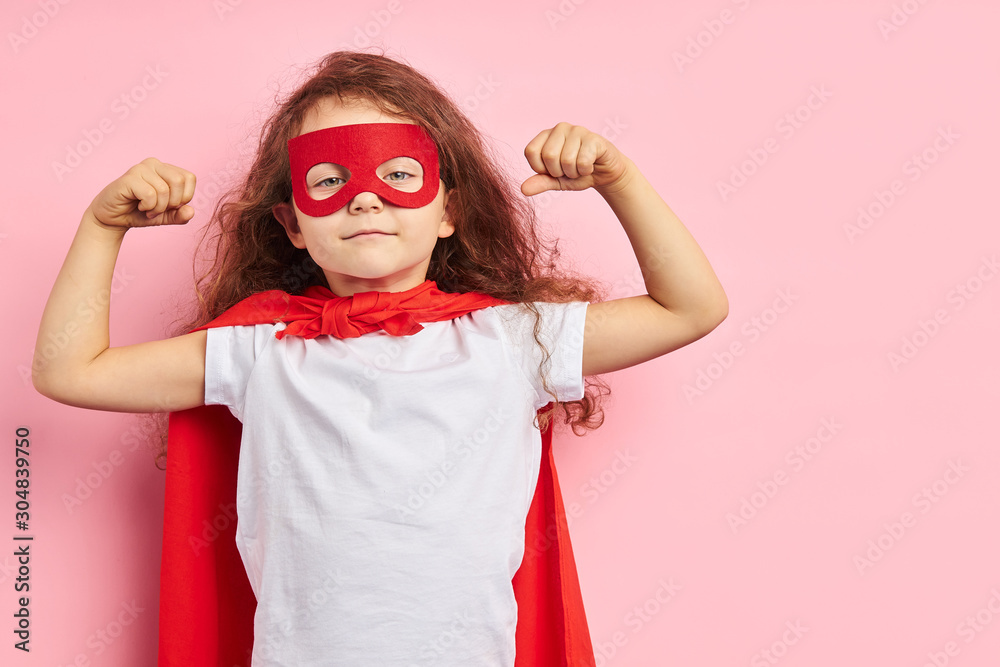 attractive little curly girl wearing red hero suit and mask showing how ...