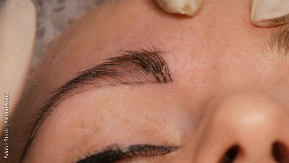 Microblading eyebrow tattoo, permanent makeup. A master in gloves ...