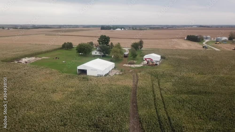 Aerial drone view in rural Iowa; flying away from a farm with barns and ...