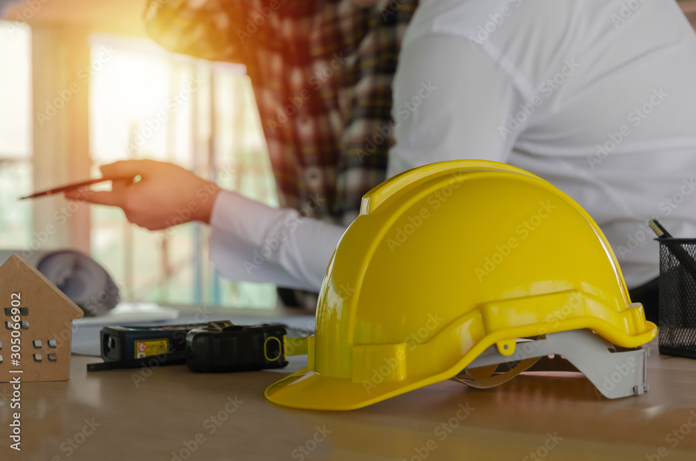 yellow safety helmet on workplace desk with construction worker team ...