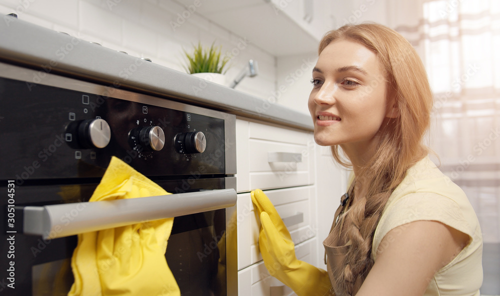 Pretty maid enjoys performing her routine chore washing the oven in the ...