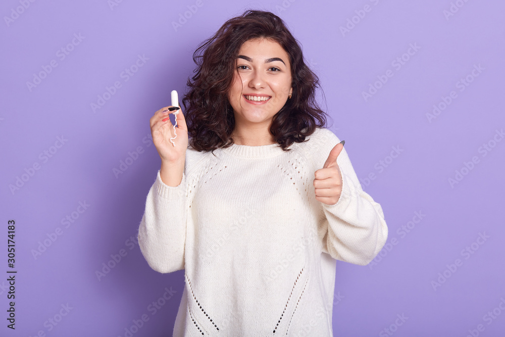 Close up portrait of female holds tampon over lilac background, having ...