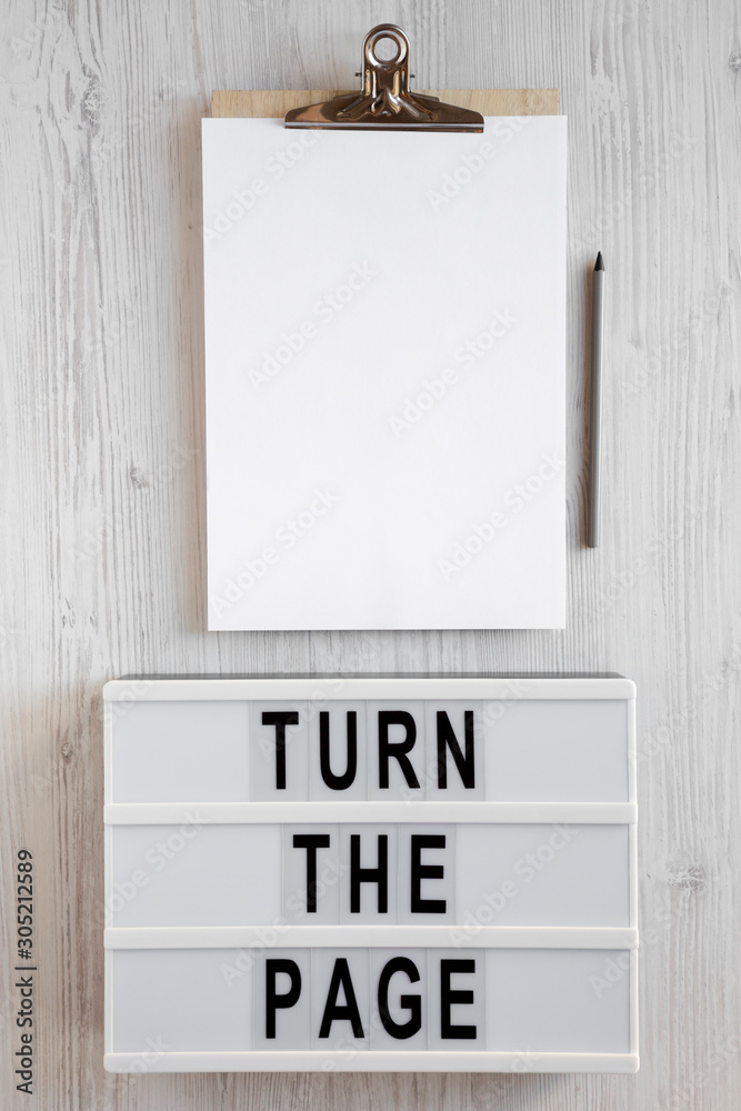 'Turn the page' words on a modern board, clipboard with blank sheet of ...