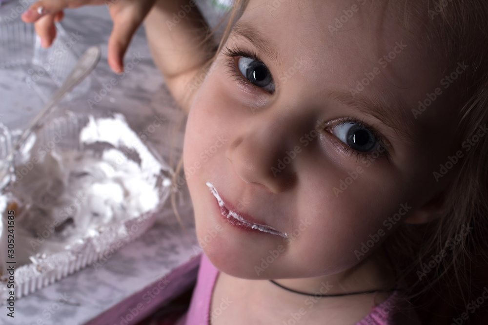Beautiful girl eating ice cream and cream with her hands. A child with ...