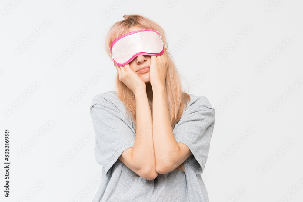 Studio portrait of sleepy young girl in grey shirt feels tired after ...