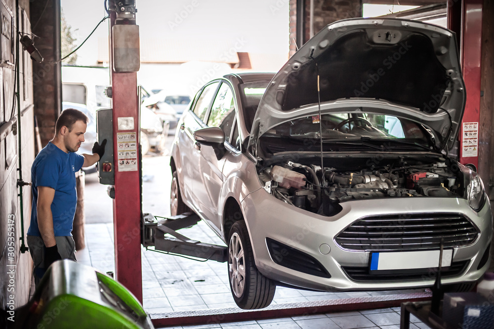 Car mechanic working in a repair garage with hydraulic car lift Stock ...