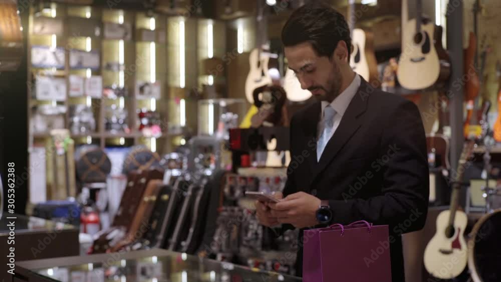 An upwardly mobile Middle Eastern man using a mobile phone to purchase ... An upwardly mobile Middle Eastern man using a mobile phone to purchase ...