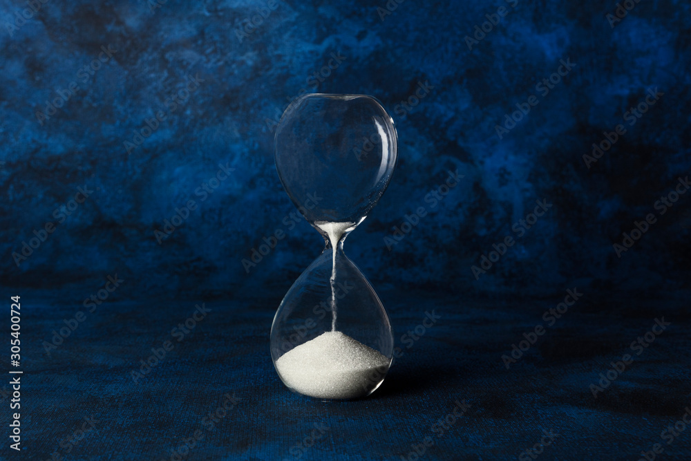 Time is running out concept. An hourglass with sand falling through, on ...