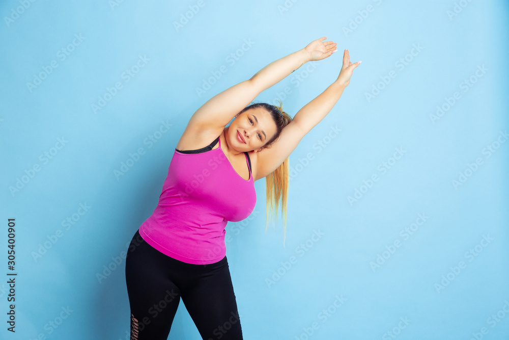 Young caucasian plus size female model's training on blue background ...