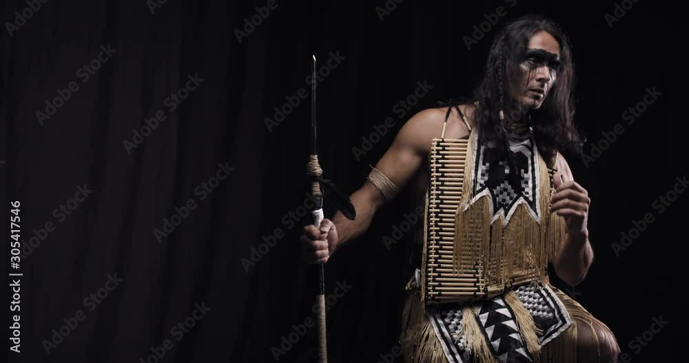 Muscular native american man in traditional costume is holding a spear ...