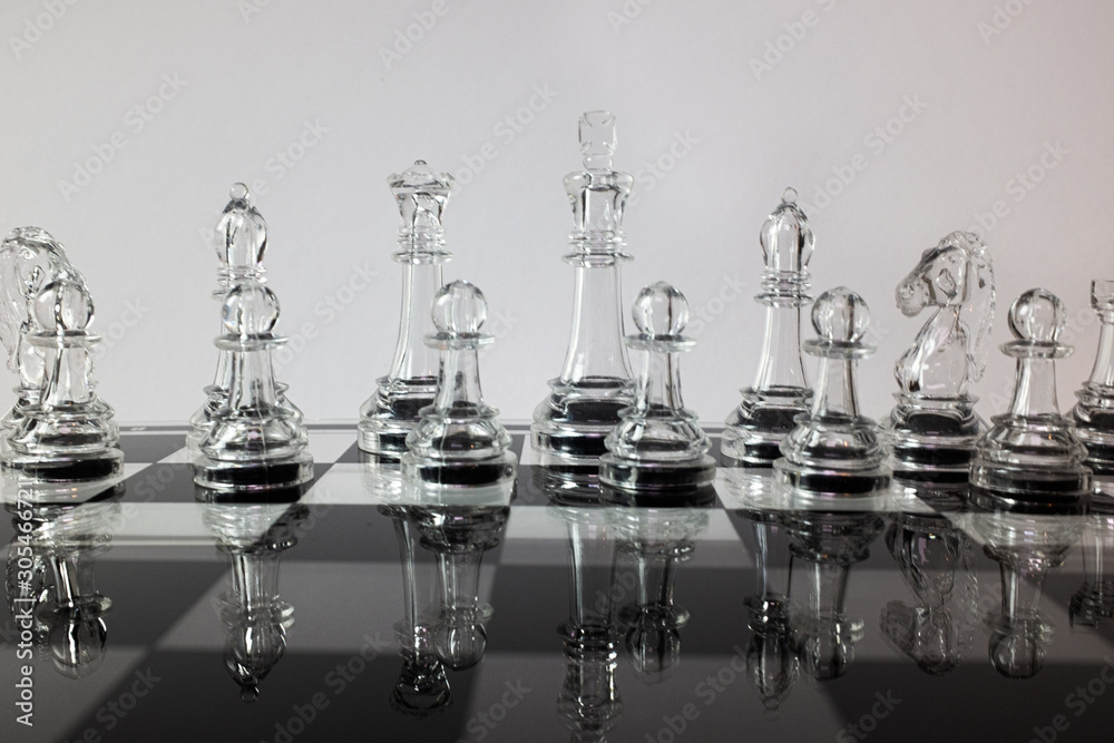 Transparent methacrylate chess pieces, front view, on a board with ...