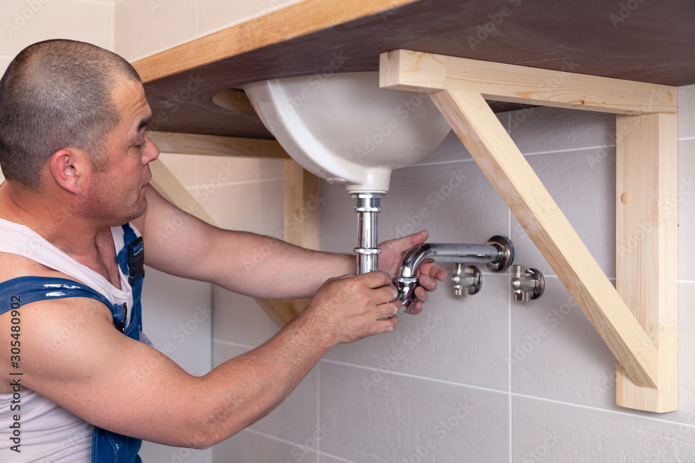 Closeup male plumber worker in blue denim uniform, overalls, fixing ...