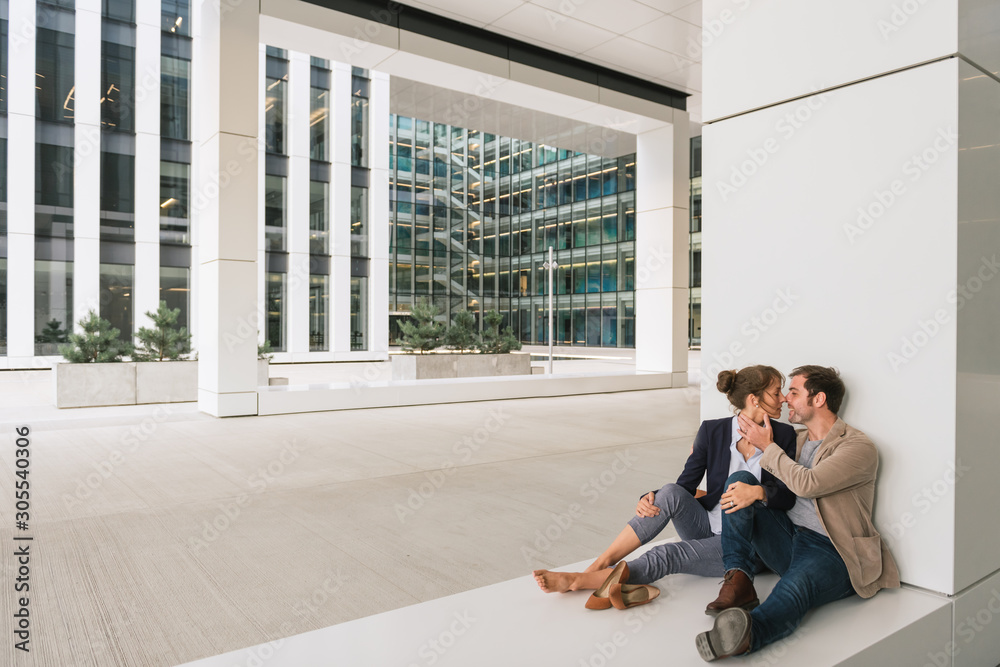 Male manager hugging and kissing girlfriend while sitting outside ...