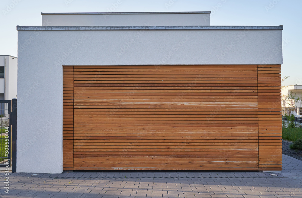 A modern Scandinavian-style garage with a wood-paneled garage door ...