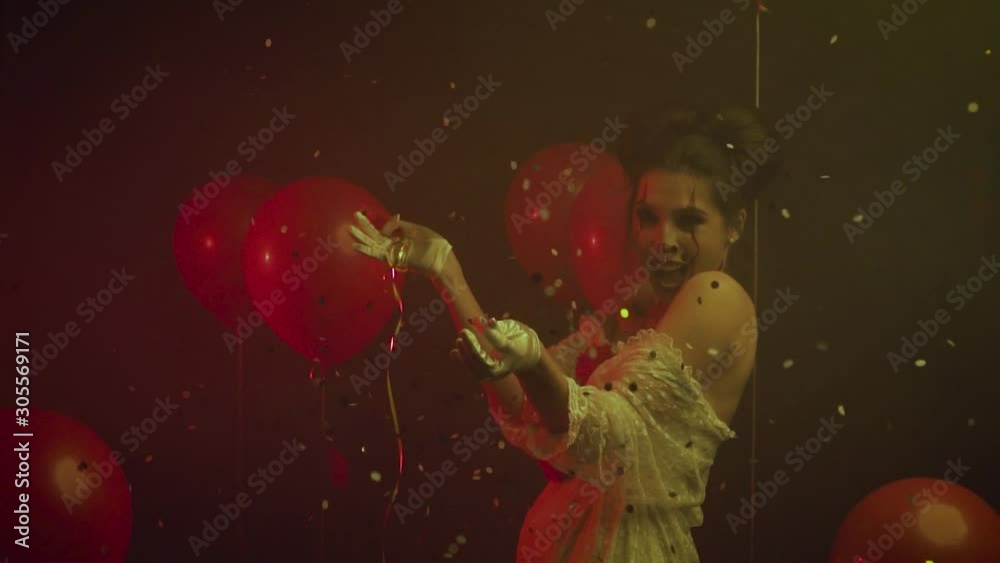 Animator woman crazy clown bursts helium balloon pops with a needle, golden serpentine sparkles ...