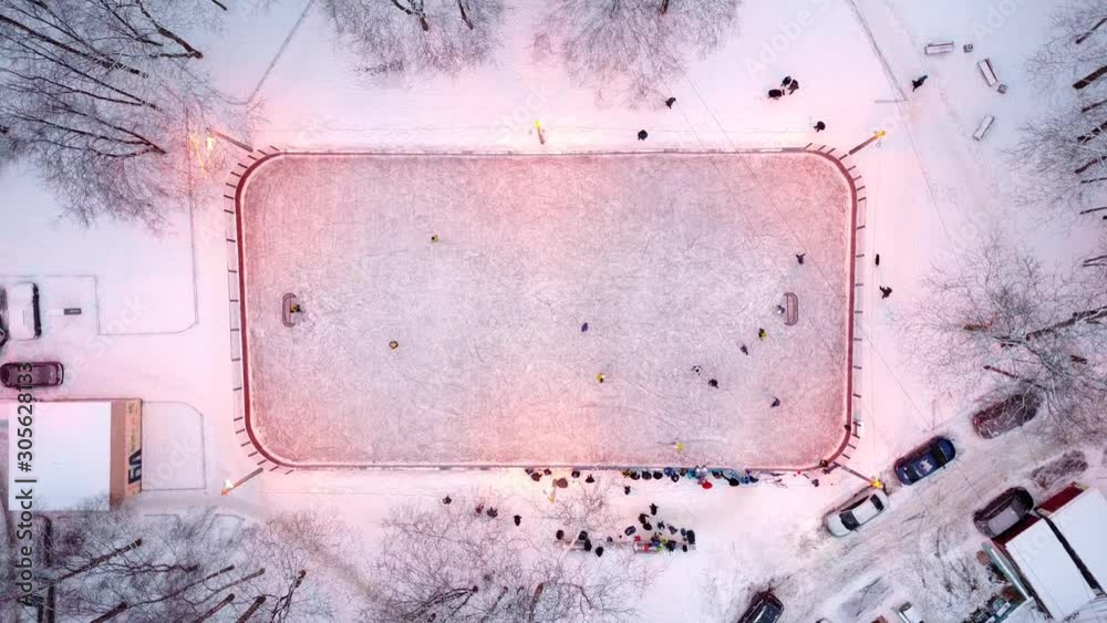 Top-down aerial shot of ice rink and young players in hockey game, few ...