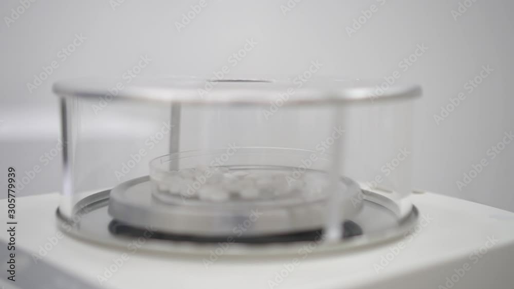 weighing the manufactured tablets, pills on the control scales. Weight ...