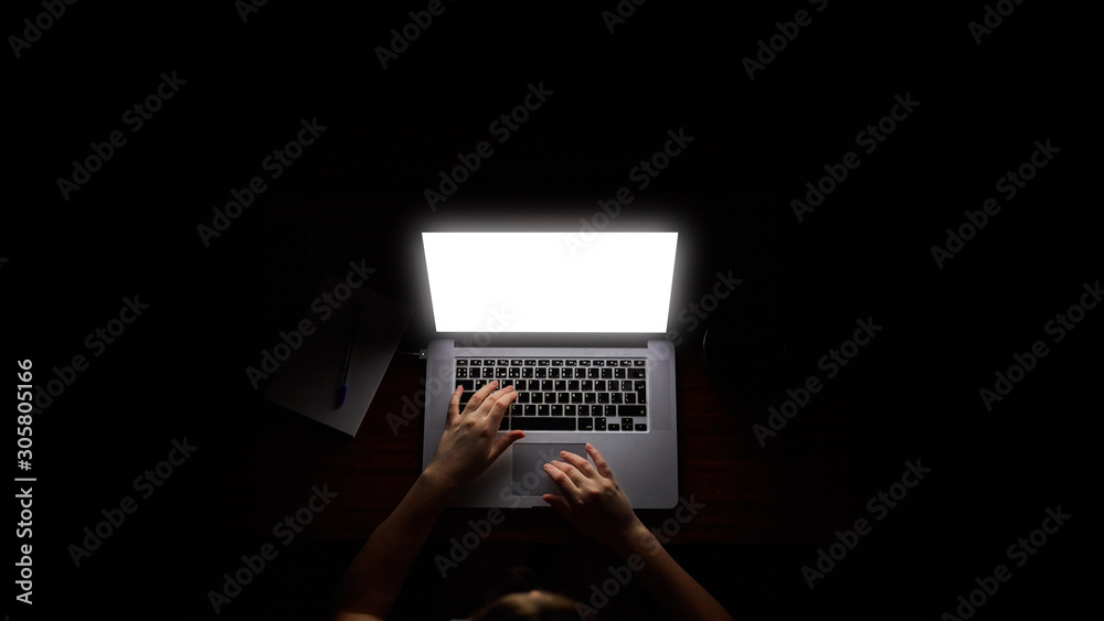 Overhead hacker in the hood working with laptop and mobile phone typing ...