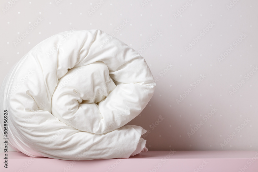 A folded, warm duvet is lying on the dressing table. Quilt for the bed ...