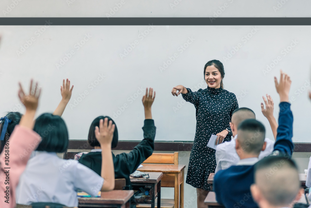 A smiling Asian female high school teacher teaches the white uniform ...