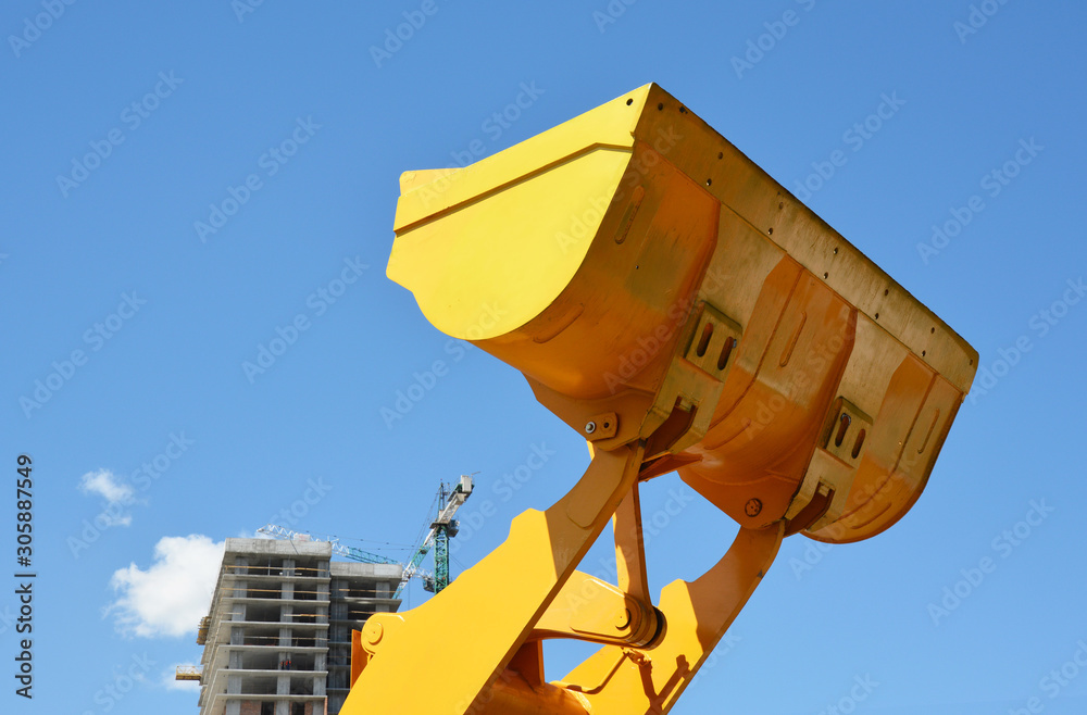Bulldozer lifting bucket. Excavator bucket with high rise building ...