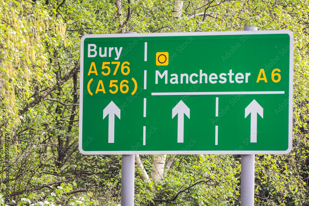 Green road signs on a leafy background showing directions to manchester ...