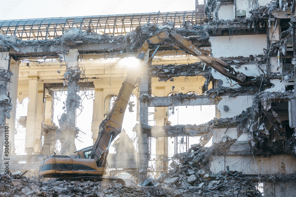 Excavator with long mechanical arm at height breaks off pieces of the ...