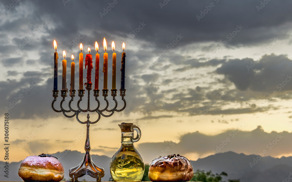 Festive donut, menorah with lights of burning candles and jar with ...
