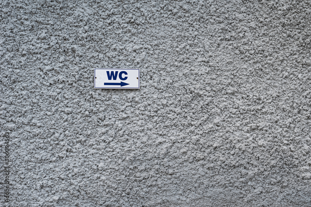 Gray plastered wall and toilet sign, patterned background, indented ...