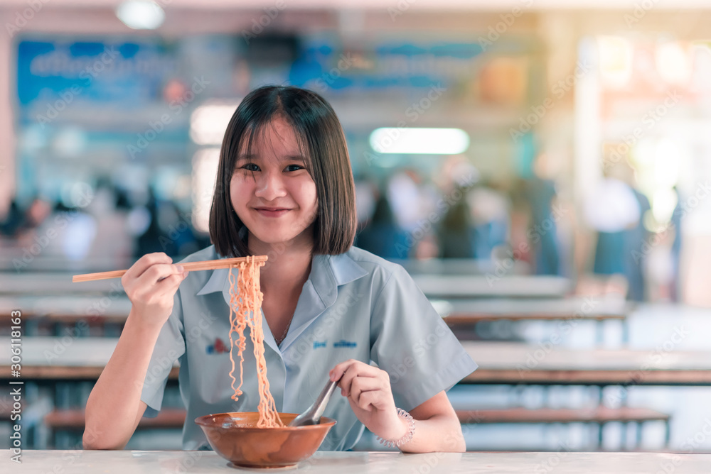 Asian female high school student in white uniform is eating delicious ...