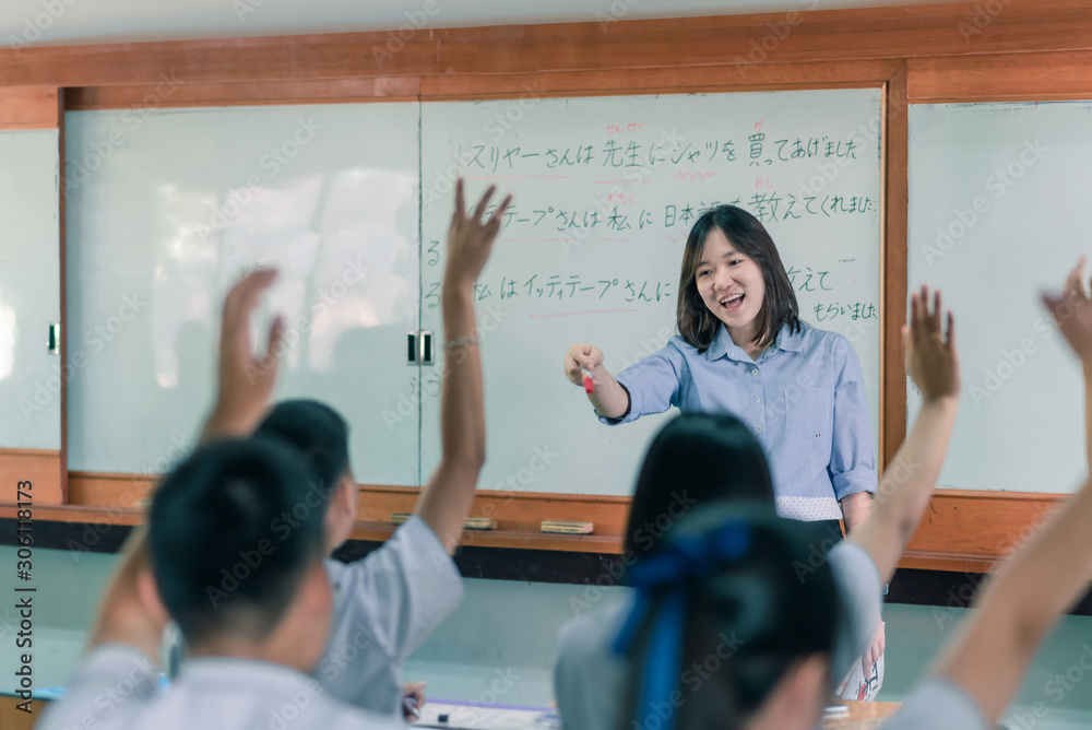 An Asian female teacher is teaching Japanese. The meaning of texts are ...