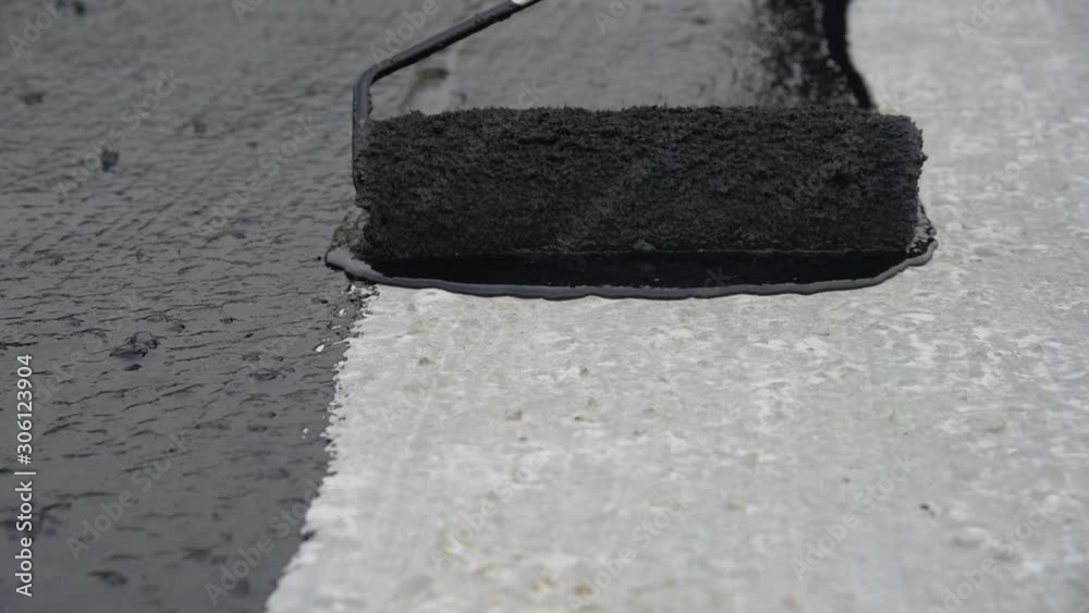 Waterproofing coating. Worker applies bitumen mastic on the foundation ...