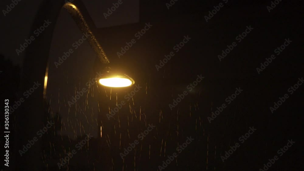Rainstorm droplets illuminated by yellow beam of street light on stormy ...