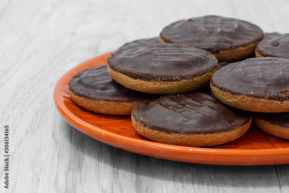 Jaffa cakes biscuits stacked on an orange plate. On a grey wood surface ...