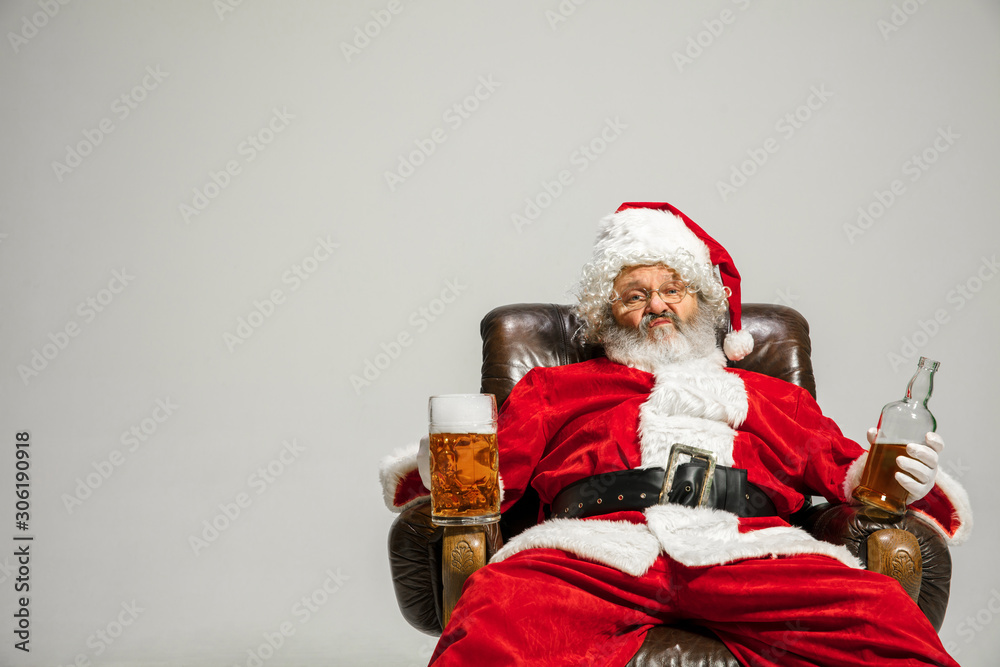 Santa Claus drinking beer sitting on armchair, congratulating, looks ...