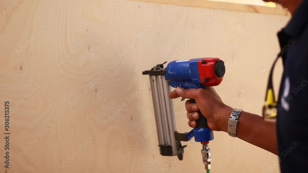 wooden carpenter using air compressor nail gun.The worker makes ...