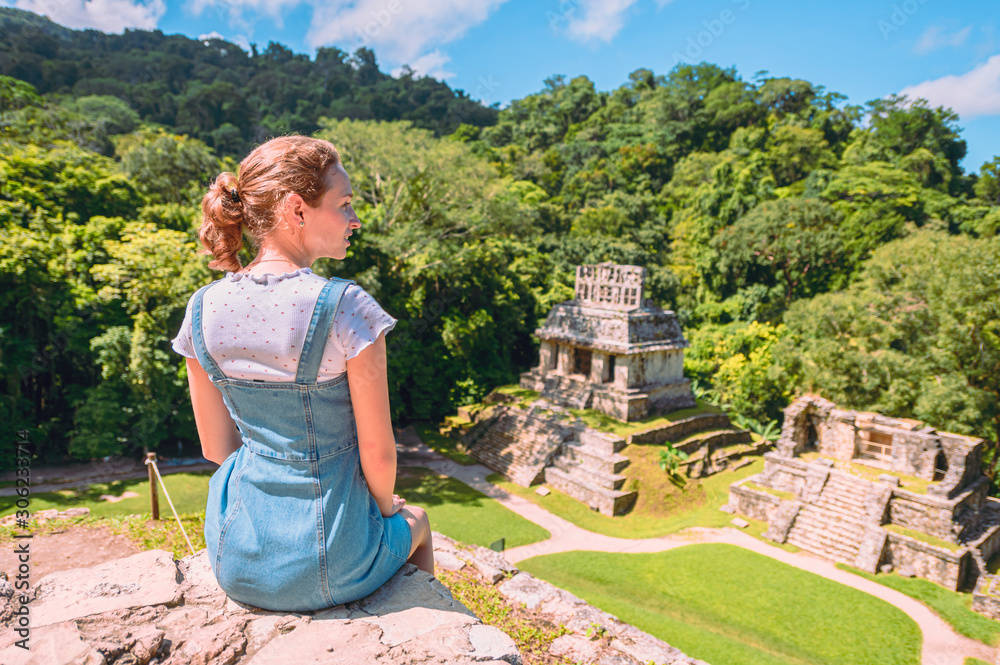 Young woman walking through the ancient Mayan ruins of Palenque ...