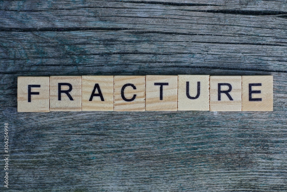word fracture made from brown wooden letters lies on a gray background ...
