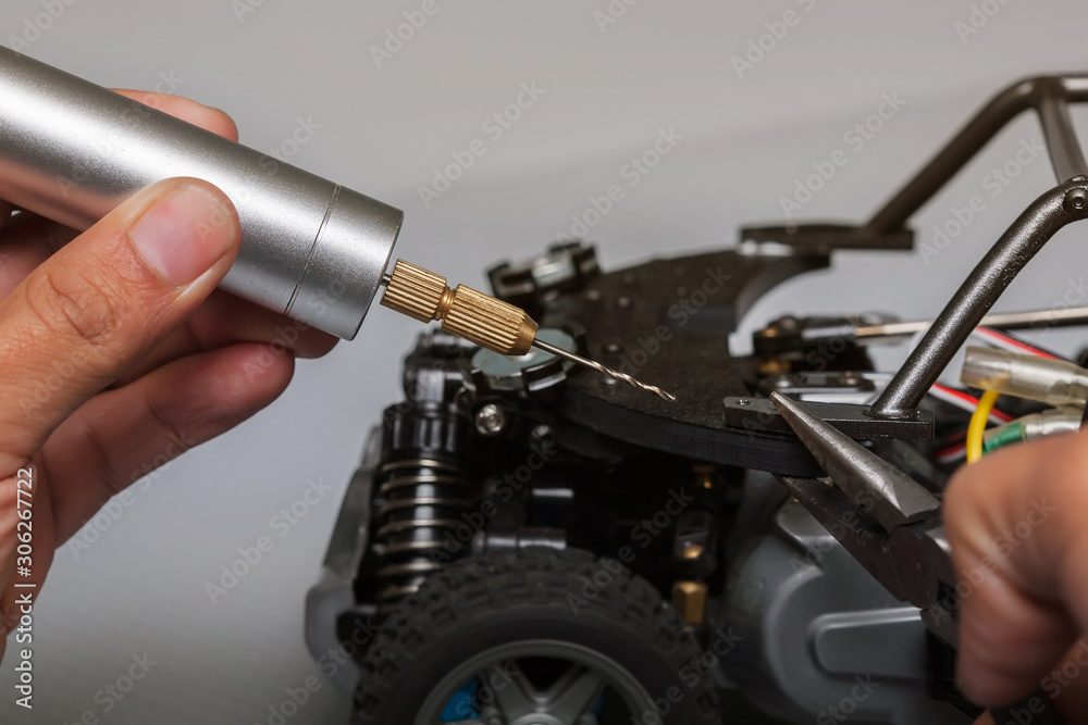 Hobbyist holding a mini drill and plyers to customize a radio ...