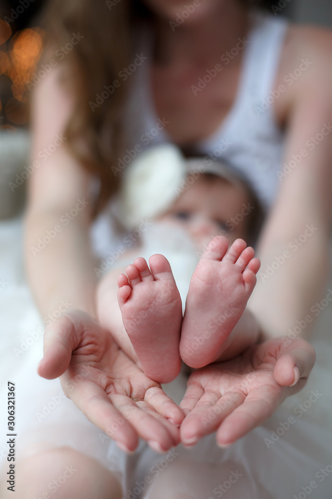 Mom gently supports the small legs of her newborn baby..Tiny newborn ...