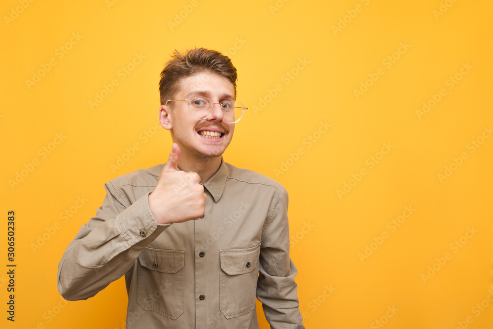 Happy nerd with mustache and glasses shows thumb up and looks into ...