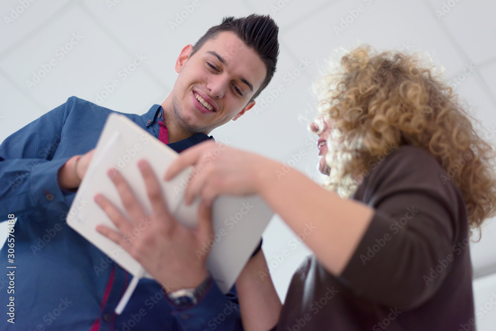 Three college students standing in corridor and using teblet and ...