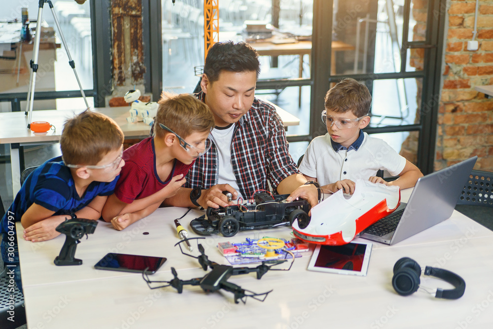 Electronic engineer with european school children working in modern ...